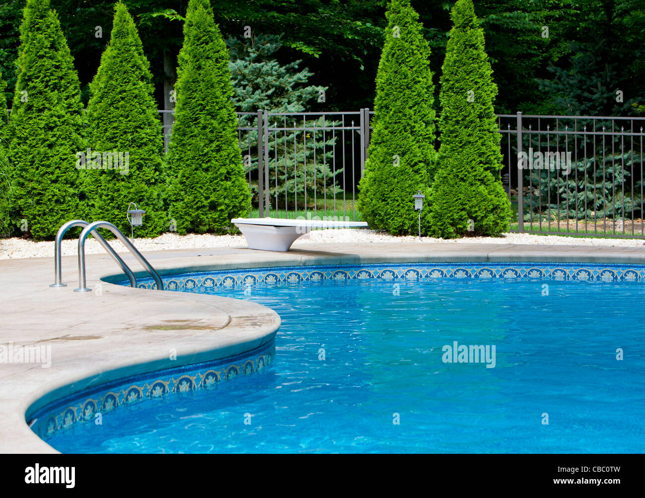 Generic small fenced swimming pool with diving board Stock Photo - Alamy