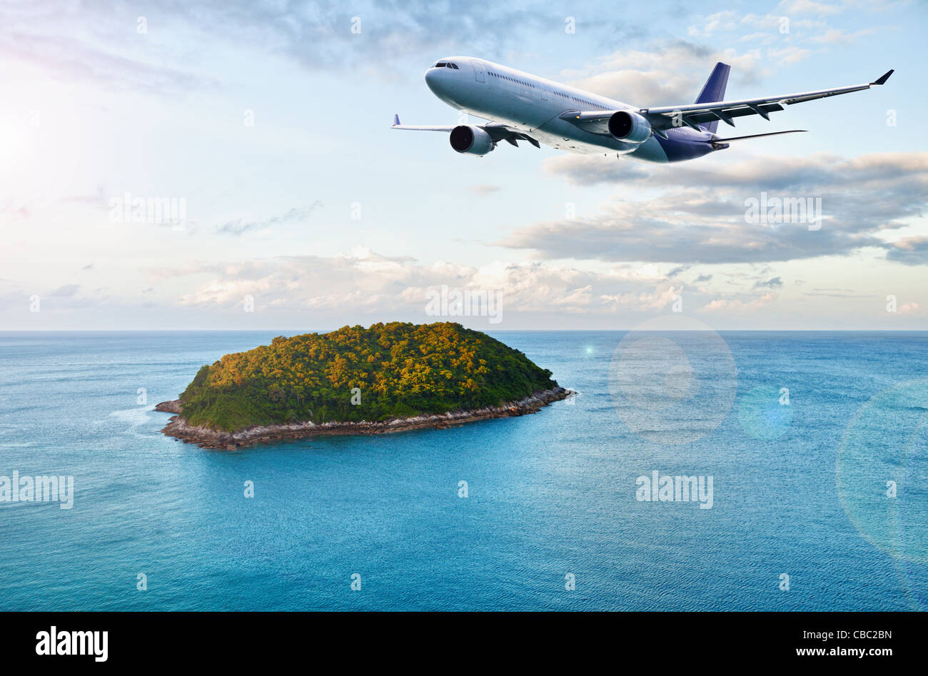 A passenger plane flies over tropical island Stock Photo - Alamy