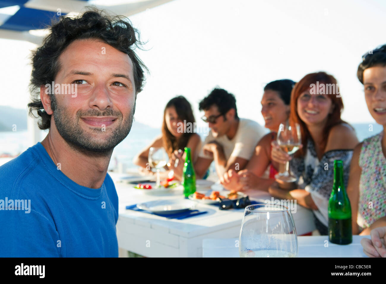 Man smiling at table with friends Stock Photo - Alamy