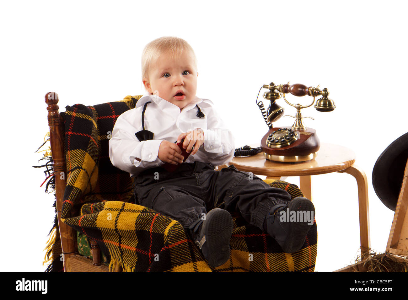Cute baby boy sitting in a chair with retro telephone Stock Photo - Alamy