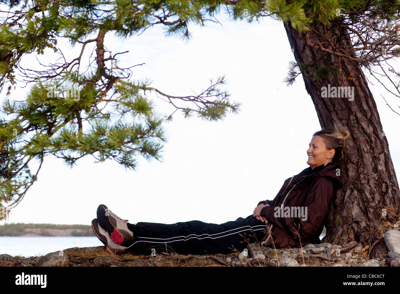 Hiker relaxing by tree Stock Photo - Alamy