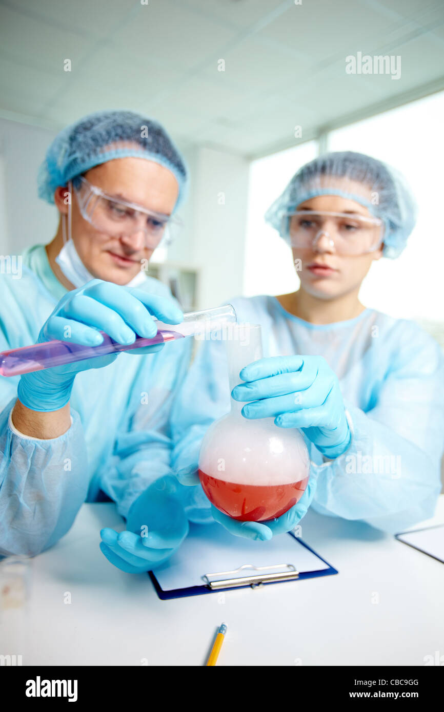 Laboratory workers mixing two chemical substances during laboratory ...