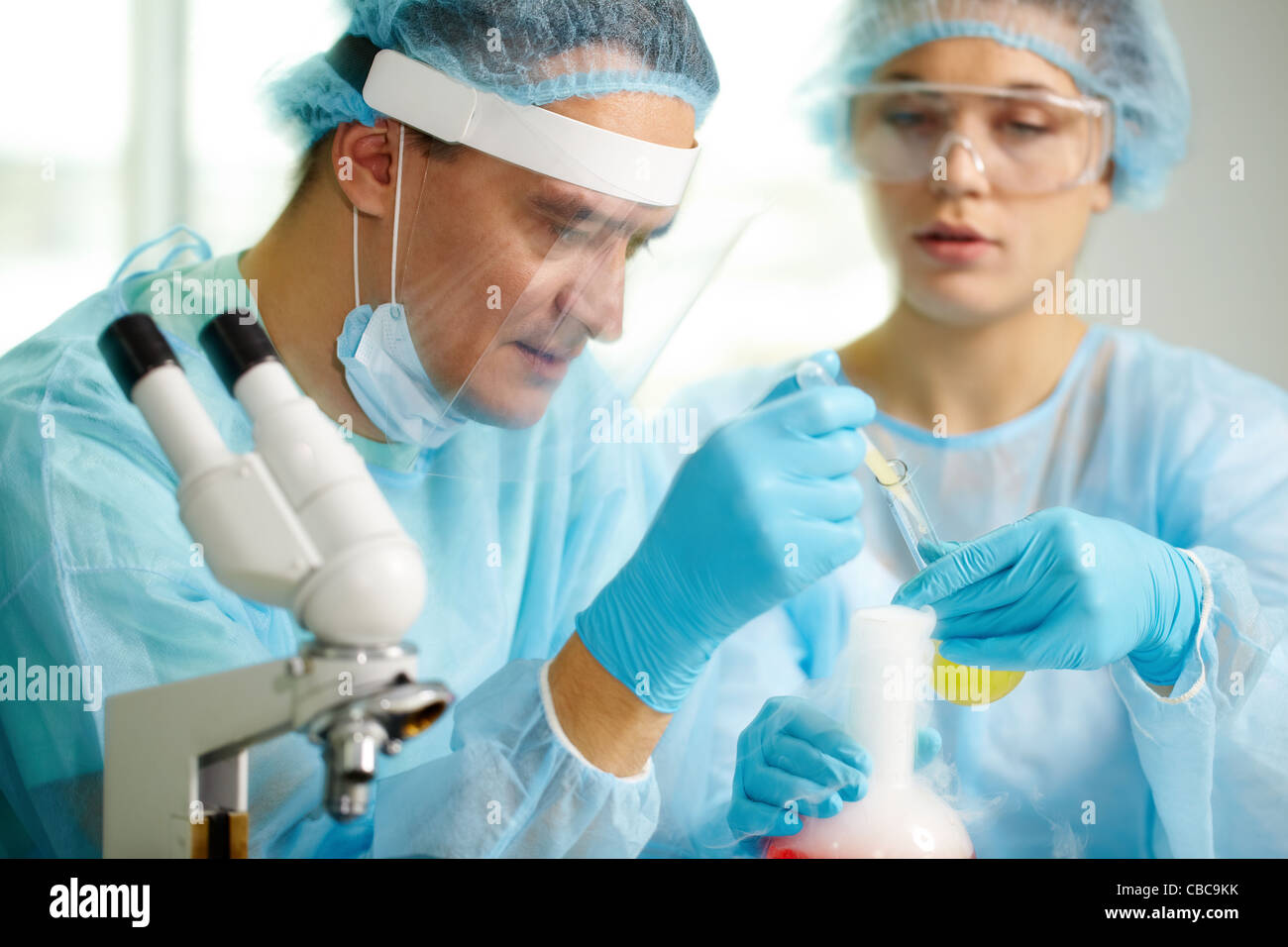 Laboratory worker is about to inject fluid into chemical substance in ...