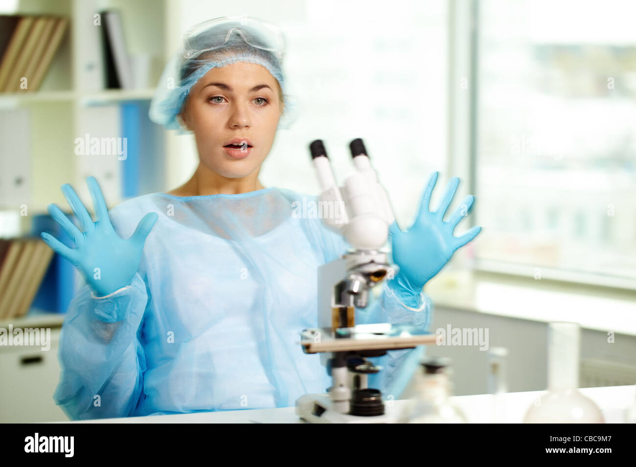 Surprised clinician looking at microscope in laboratory Stock Photo - Alamy