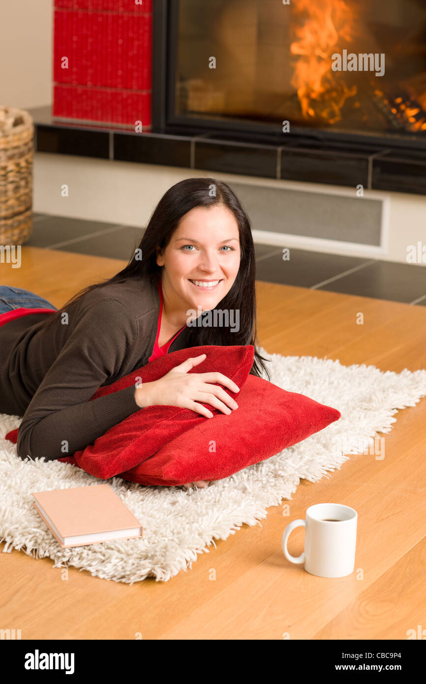 Happy young woman lying on rug by fireplace home living Stock Photo - Alamy