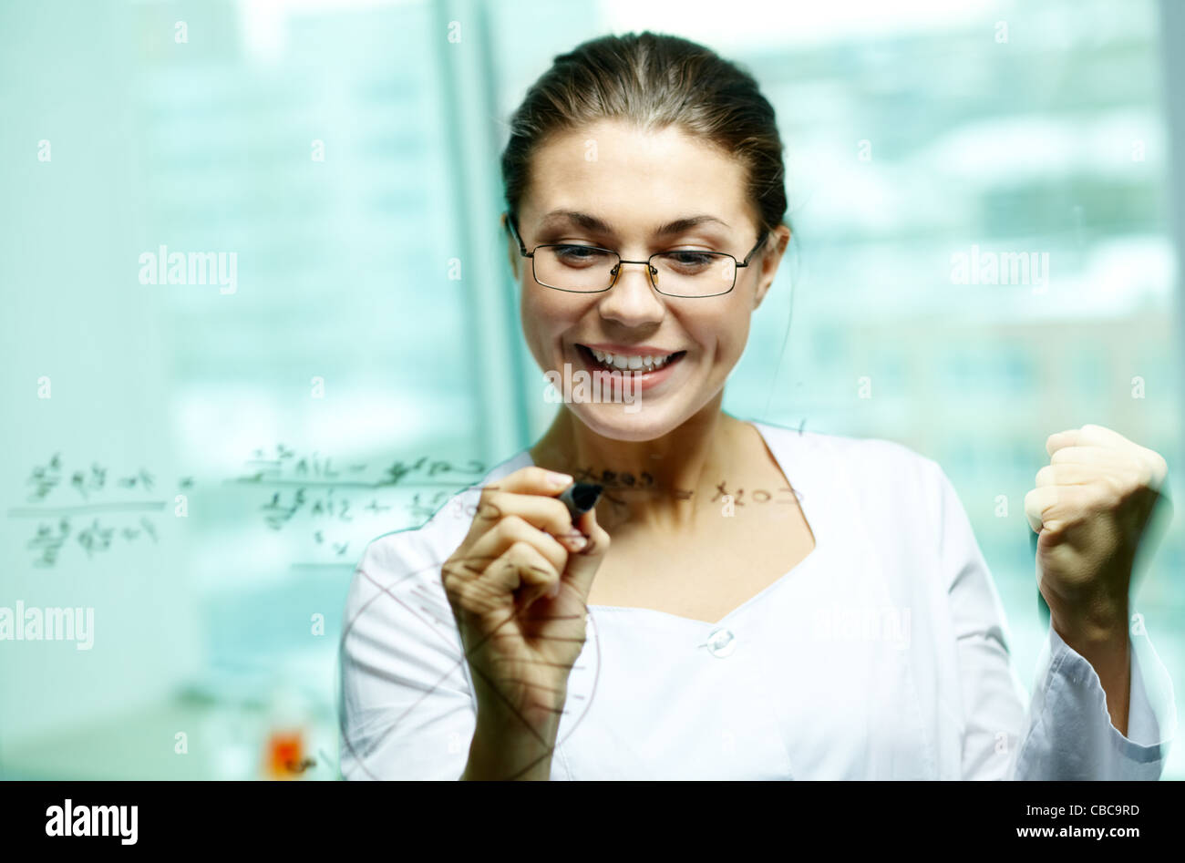 Happy young woman looking at board while writing on it Stock Photo - Alamy