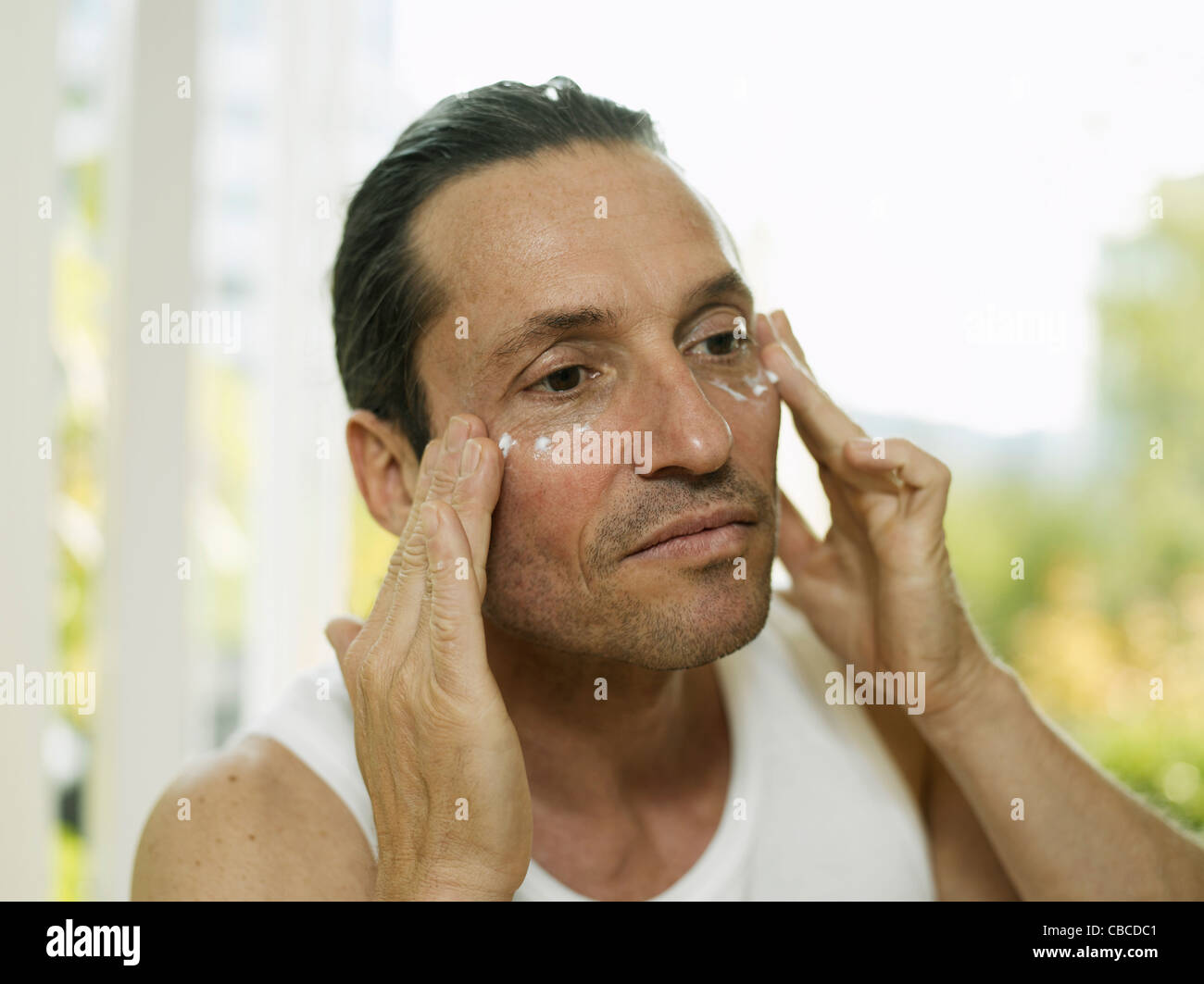 Man applying moisturizer to face Stock Photo - Alamy