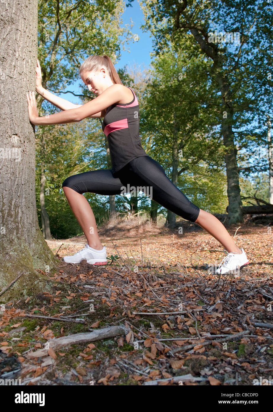 Runner stretching against tree in park Stock Photo - Alamy