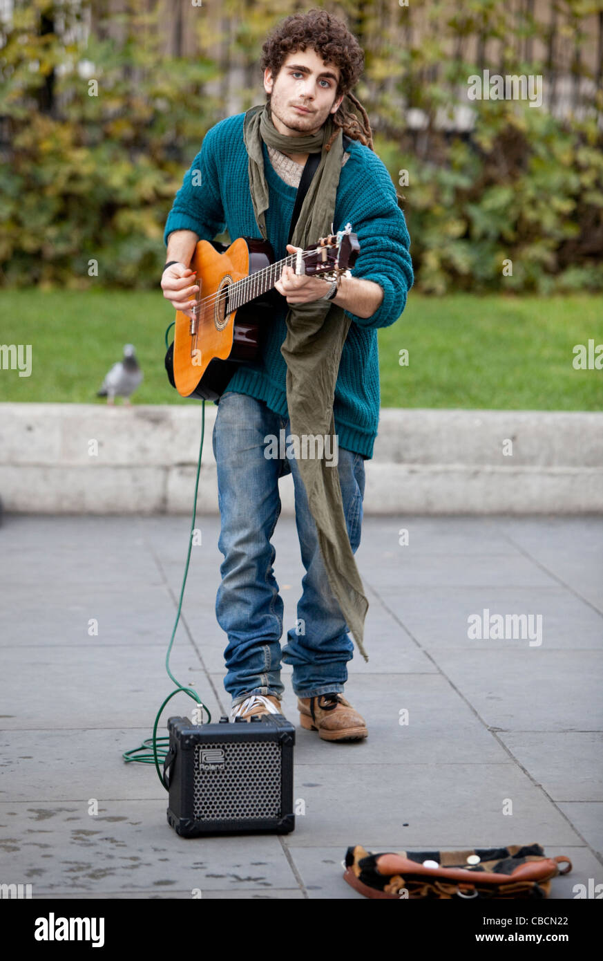 Male street busker playing a guitar on the pavement, London, England ...