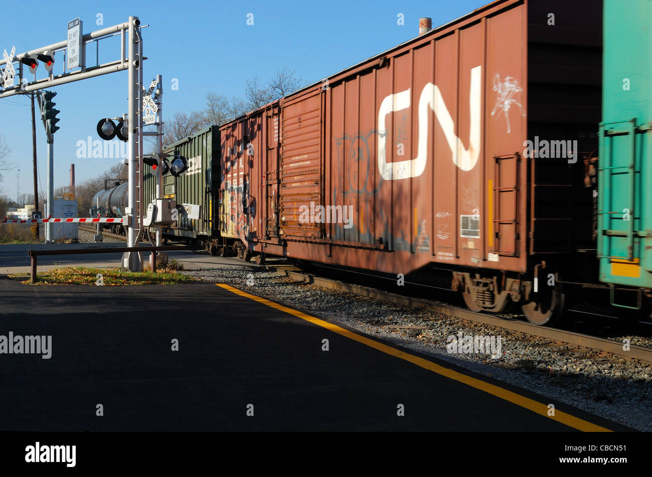 Freight train passes through road intersection Stock Photo - Alamy