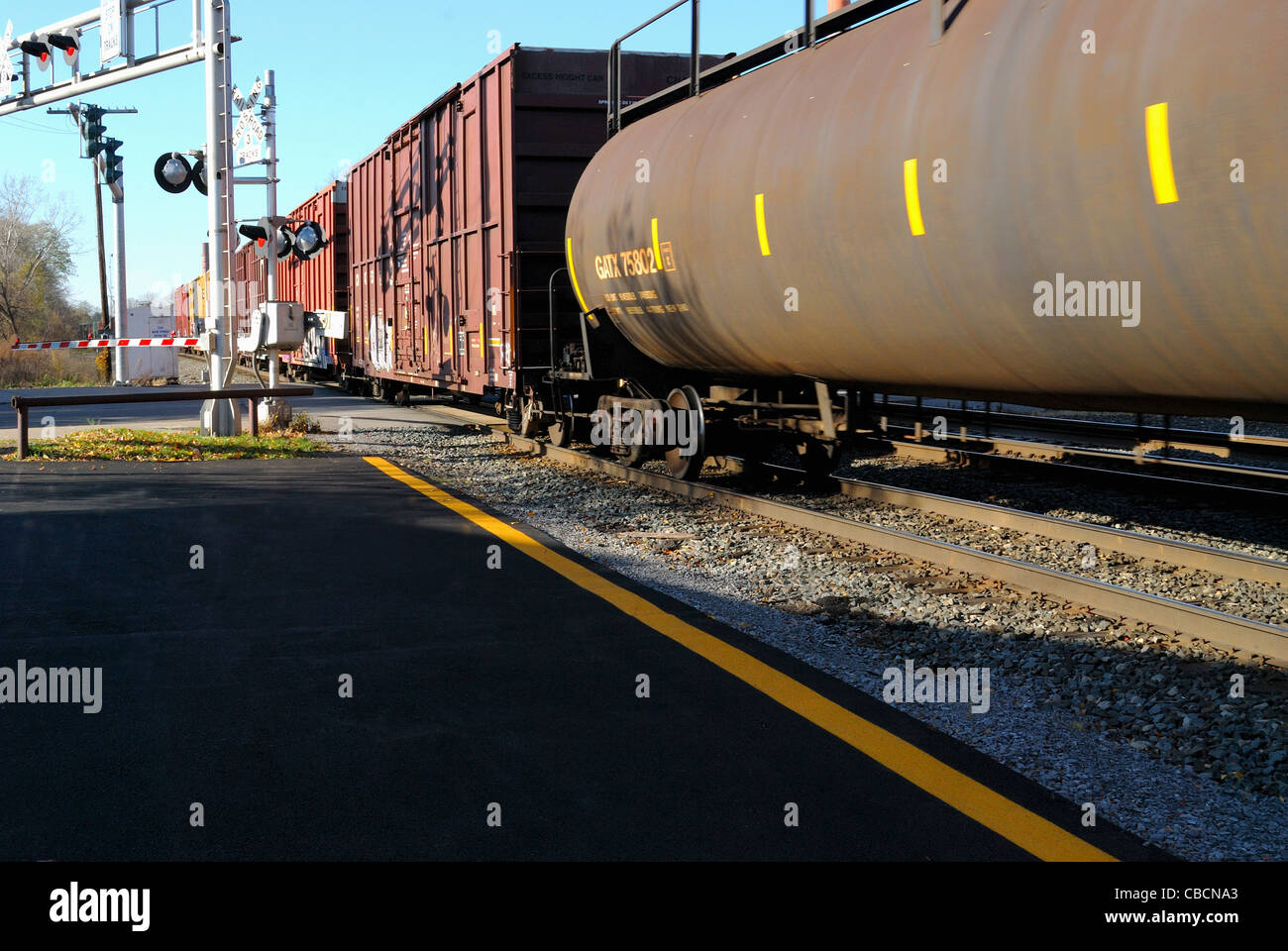 Freight train passes through road intersection Stock Photo - Alamy