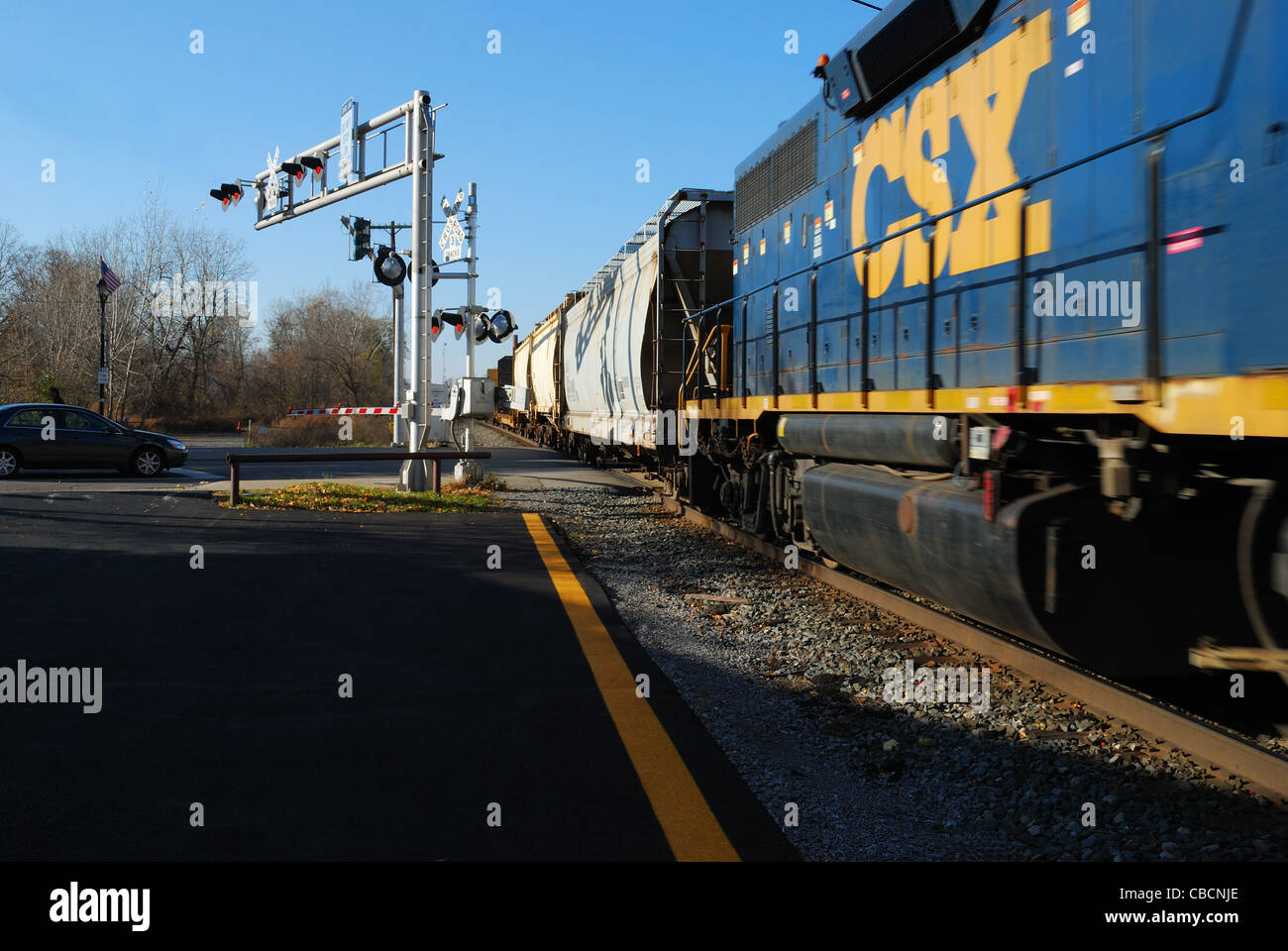 Freight train passes through road intersection Stock Photo - Alamy