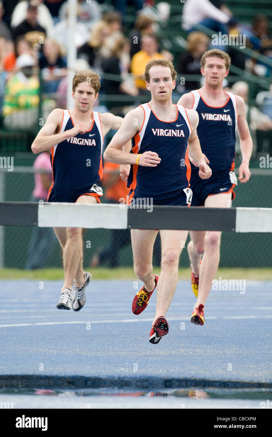 Three male runners approach a hurdle in a steeplechase race before a ...