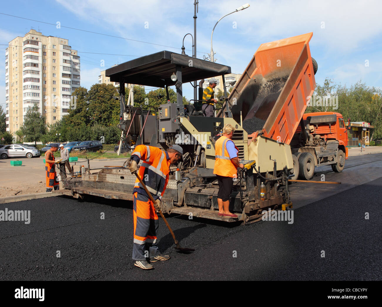 Road construction crew apply the first layer of asphalt on a paving ...
