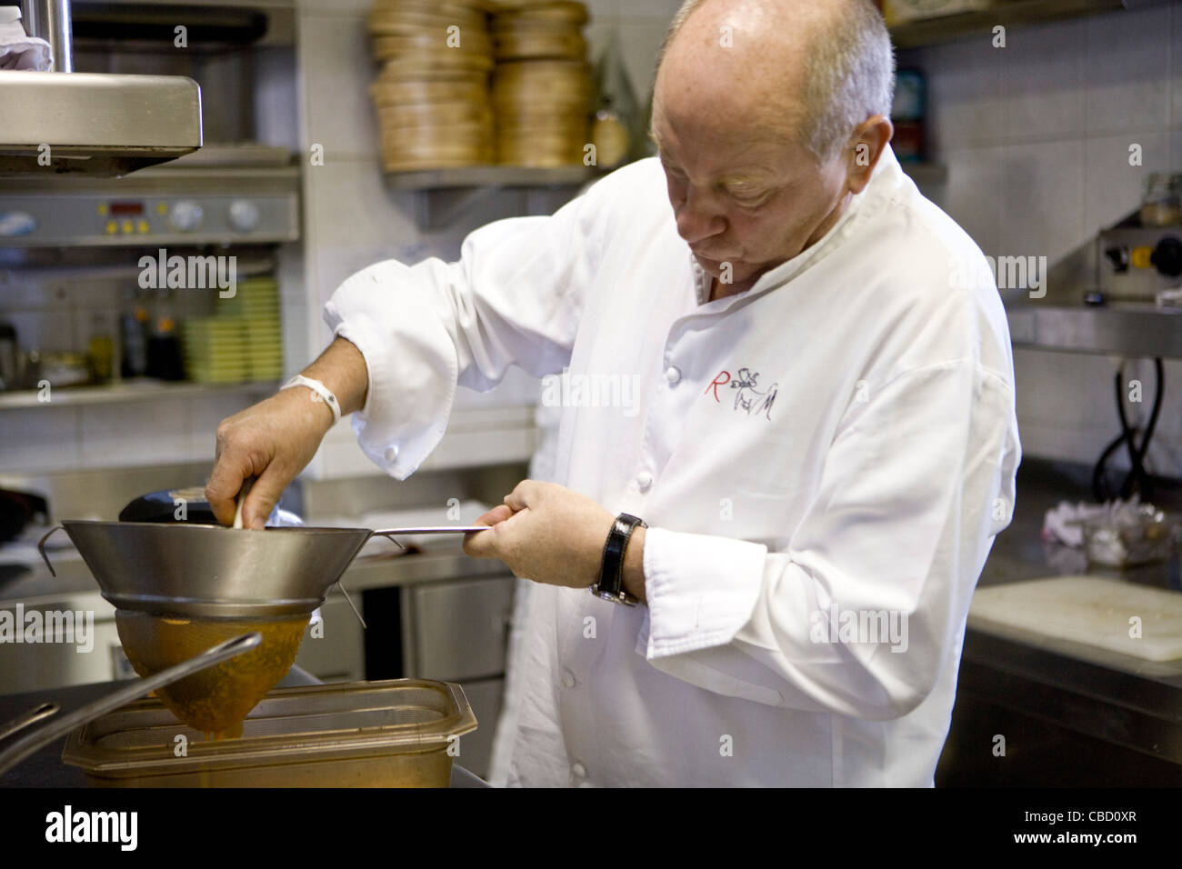 Chef straining food through strainer Stock Photo - Alamy