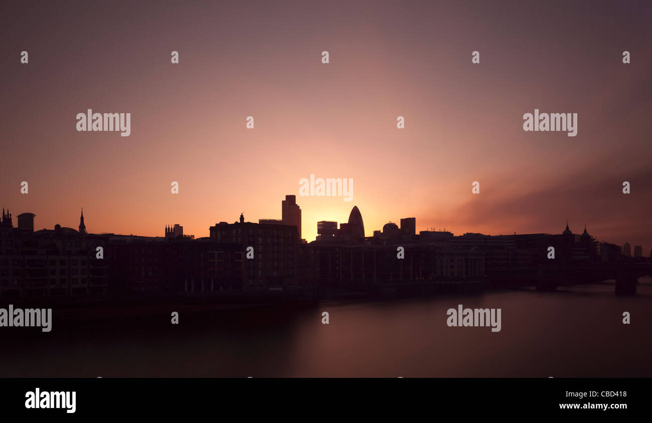 Sun rising over urban buildings on river Stock Photo - Alamy