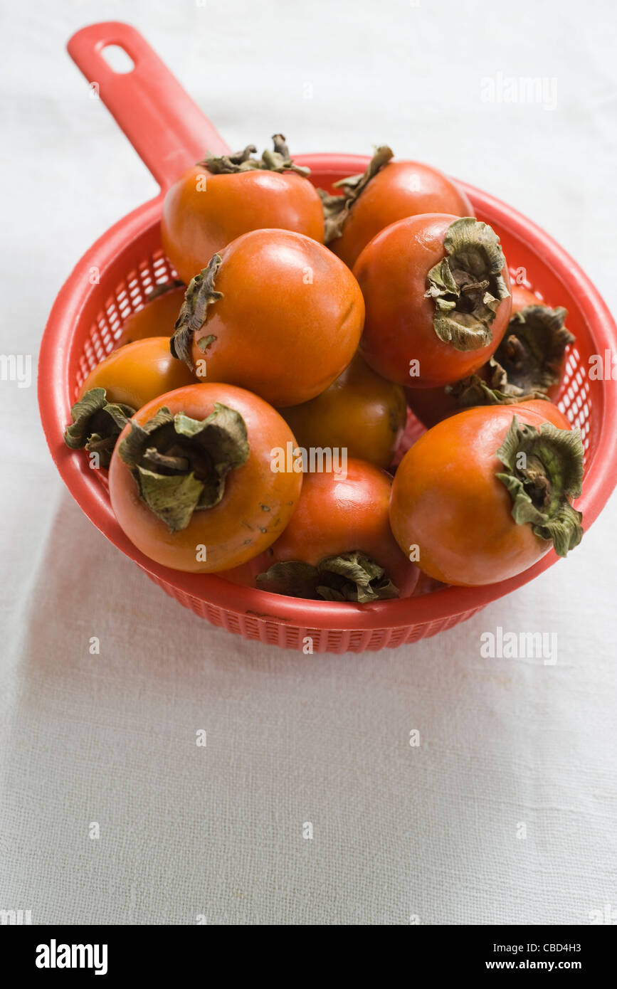 Ripe persimmons in colander Stock Photo - Alamy