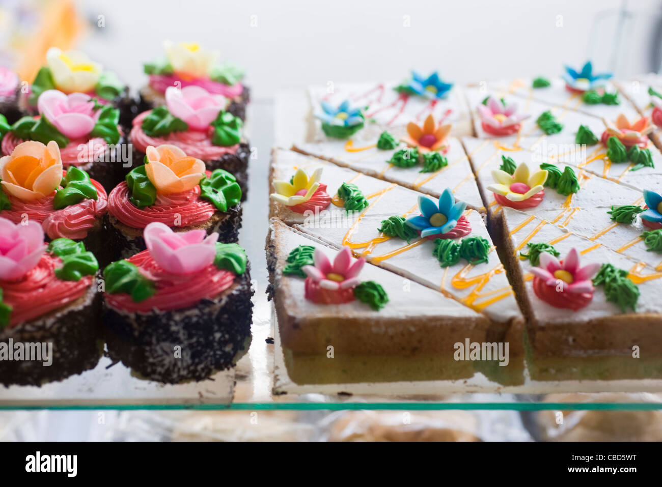 Cakes decorated with icing and sprinkles on display shelf Stock Photo ...