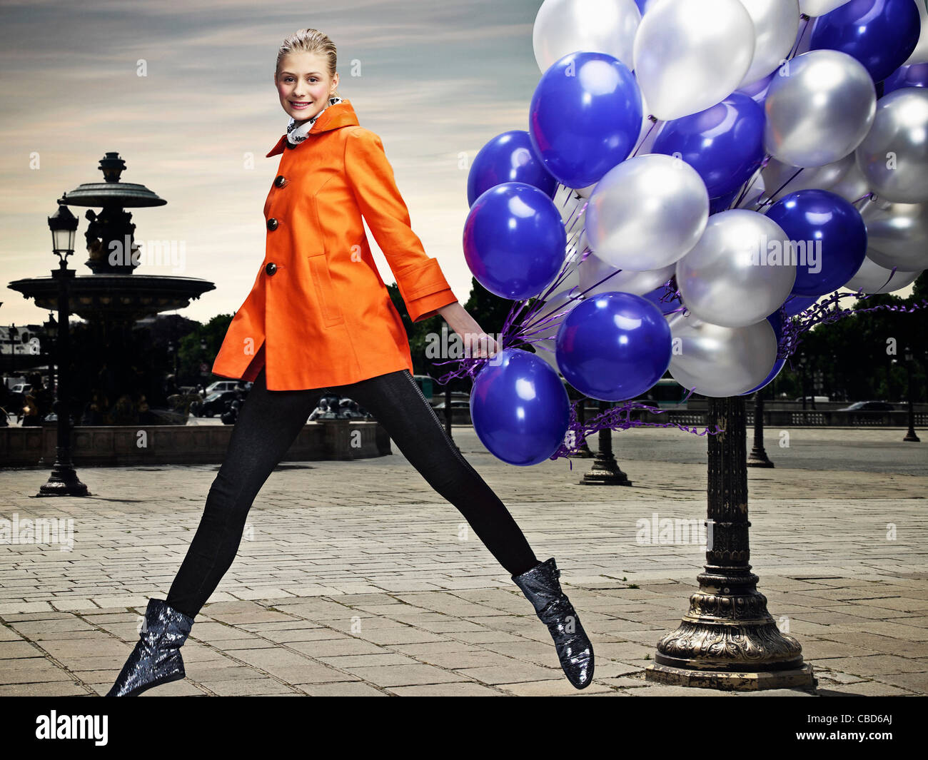 Woman carrying balloons on city street Stock Photo - Alamy