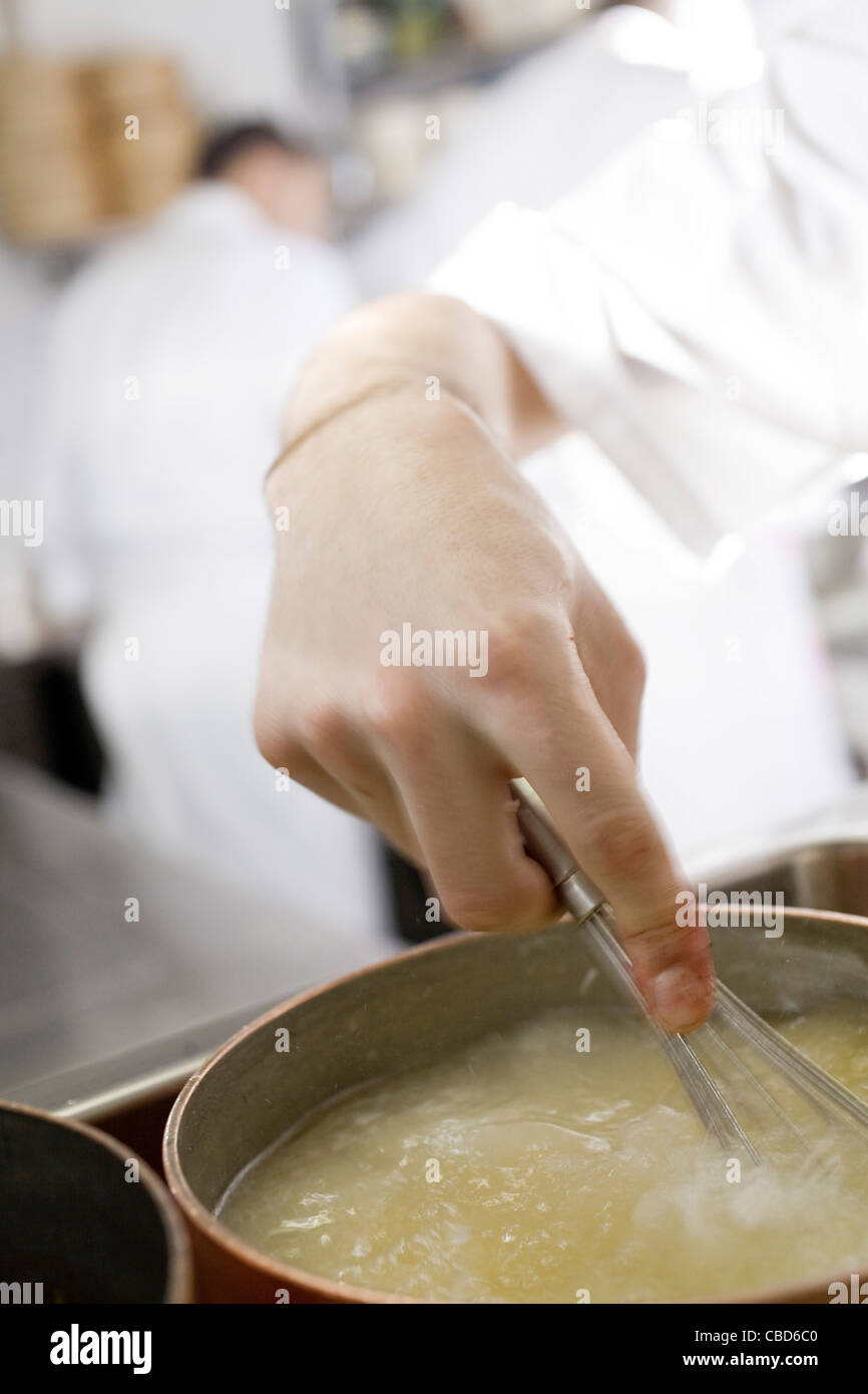 Chef using whisk to stir contents of pot, cropped Stock Photo - Alamy