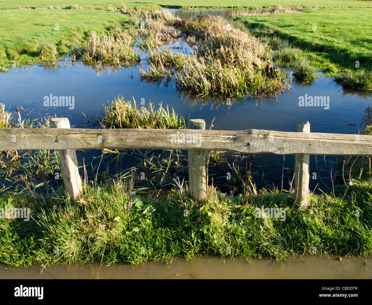 A low wooden fence in front of a drainage ditch on common land Stock ...