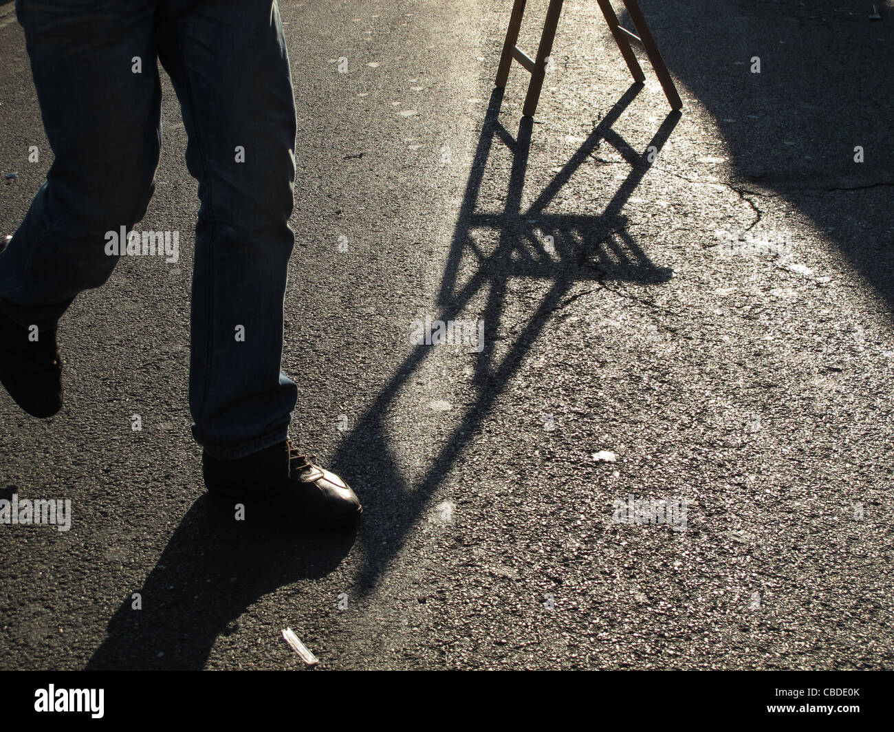 man walking with shadow of chair in street road in city town Stock ...