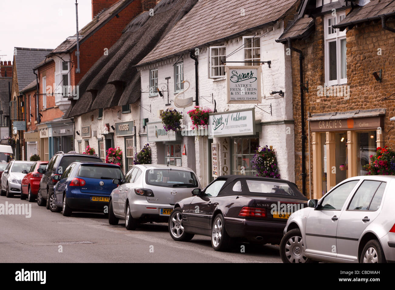 Old shop fronts, signs and parked cars along town centre shopping ...