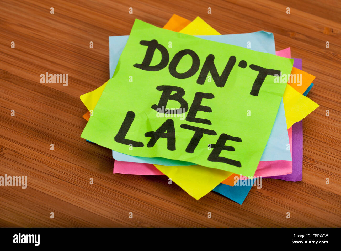don't be late reminder - stack of color sticky notes against wooden ...