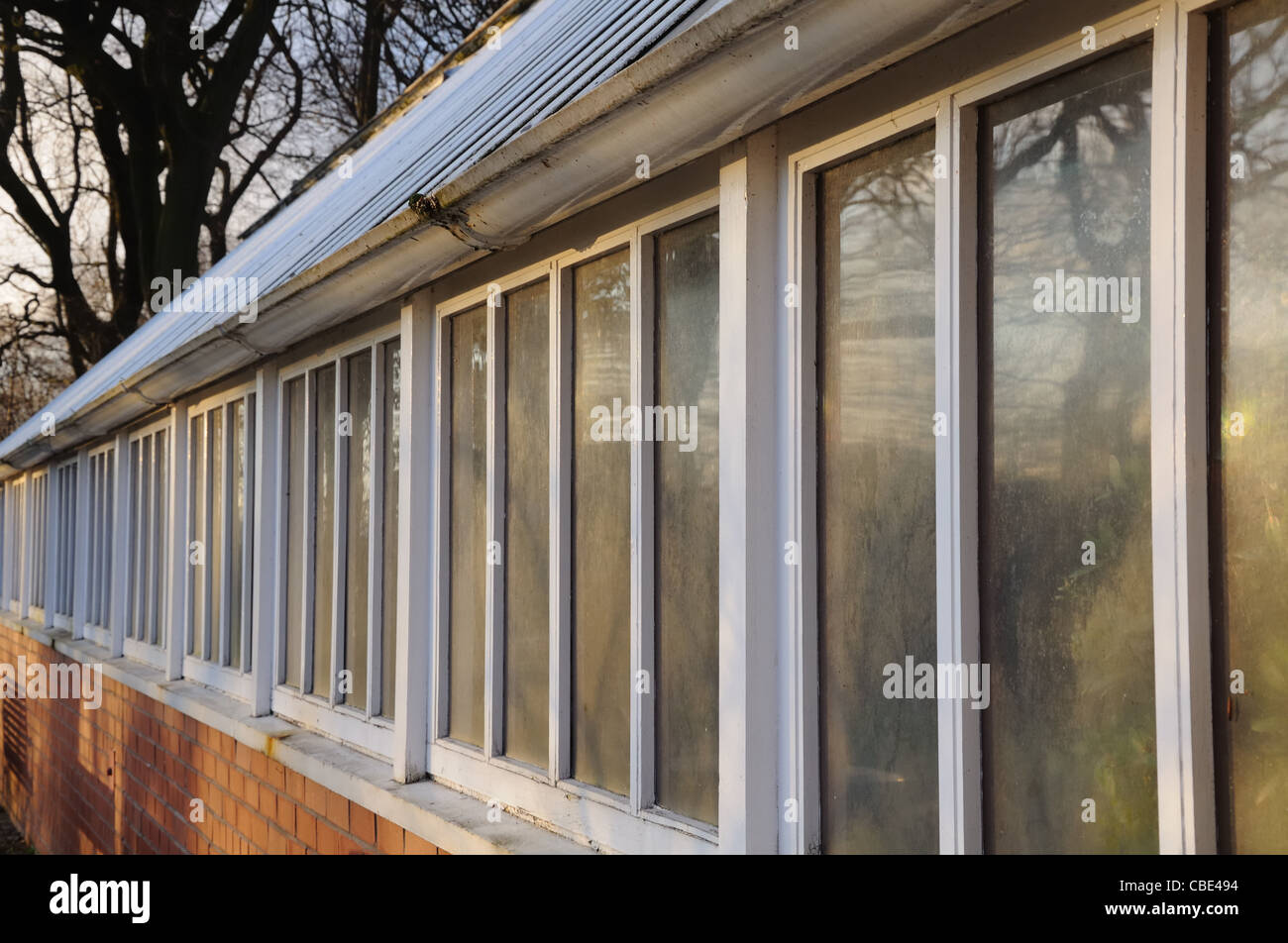 Long row of dirty windows, gutter and roof glass of commercial ...