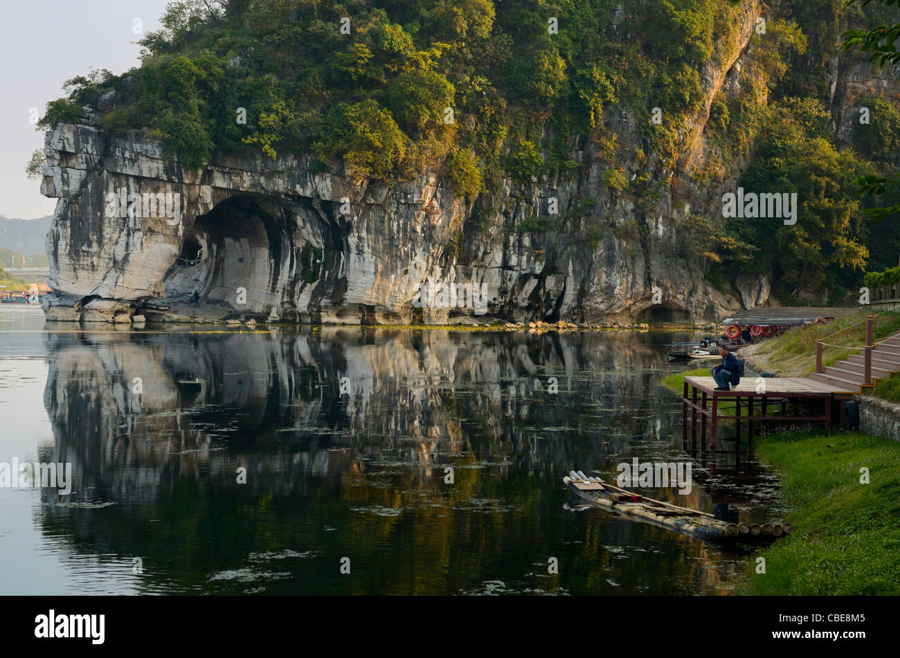 Man fishing from dock with Water Moon Cave of Elephant Trunk Hill Park ...