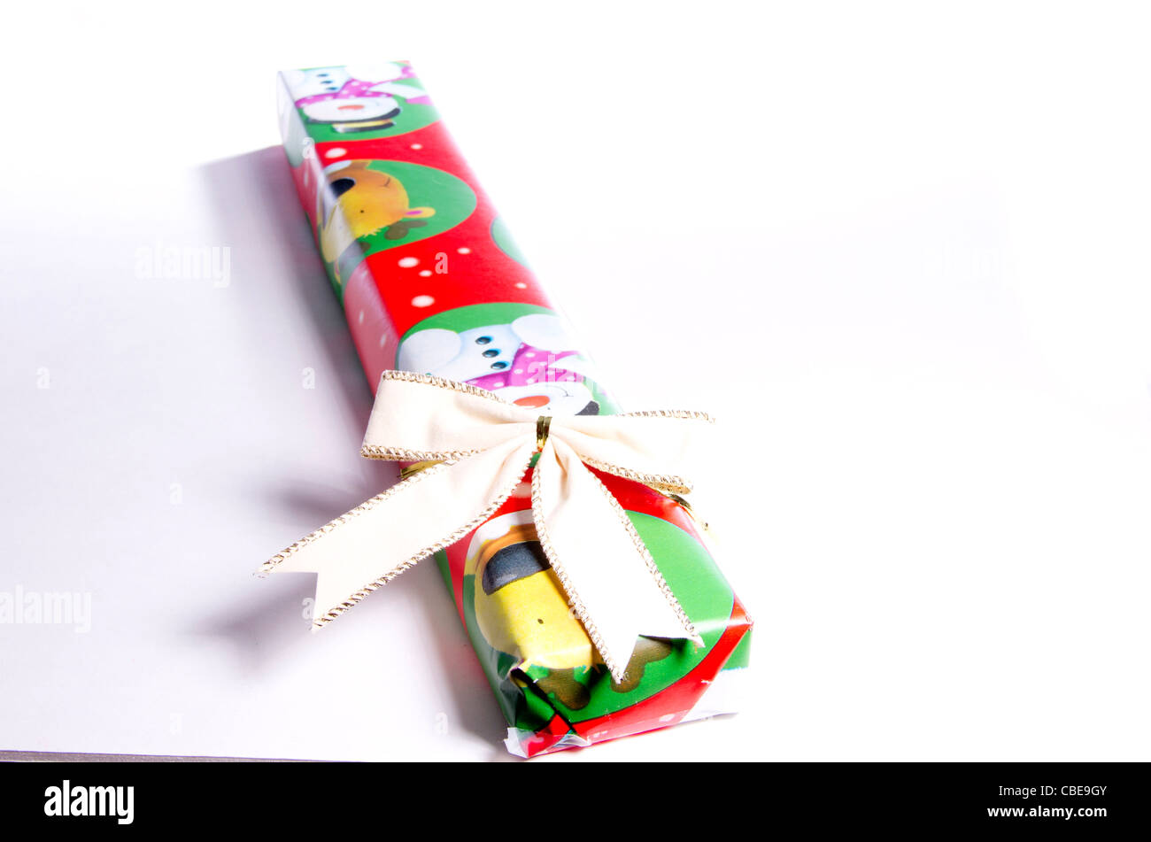 A long, rectangular Christmas present with a white velvet bow on it ...