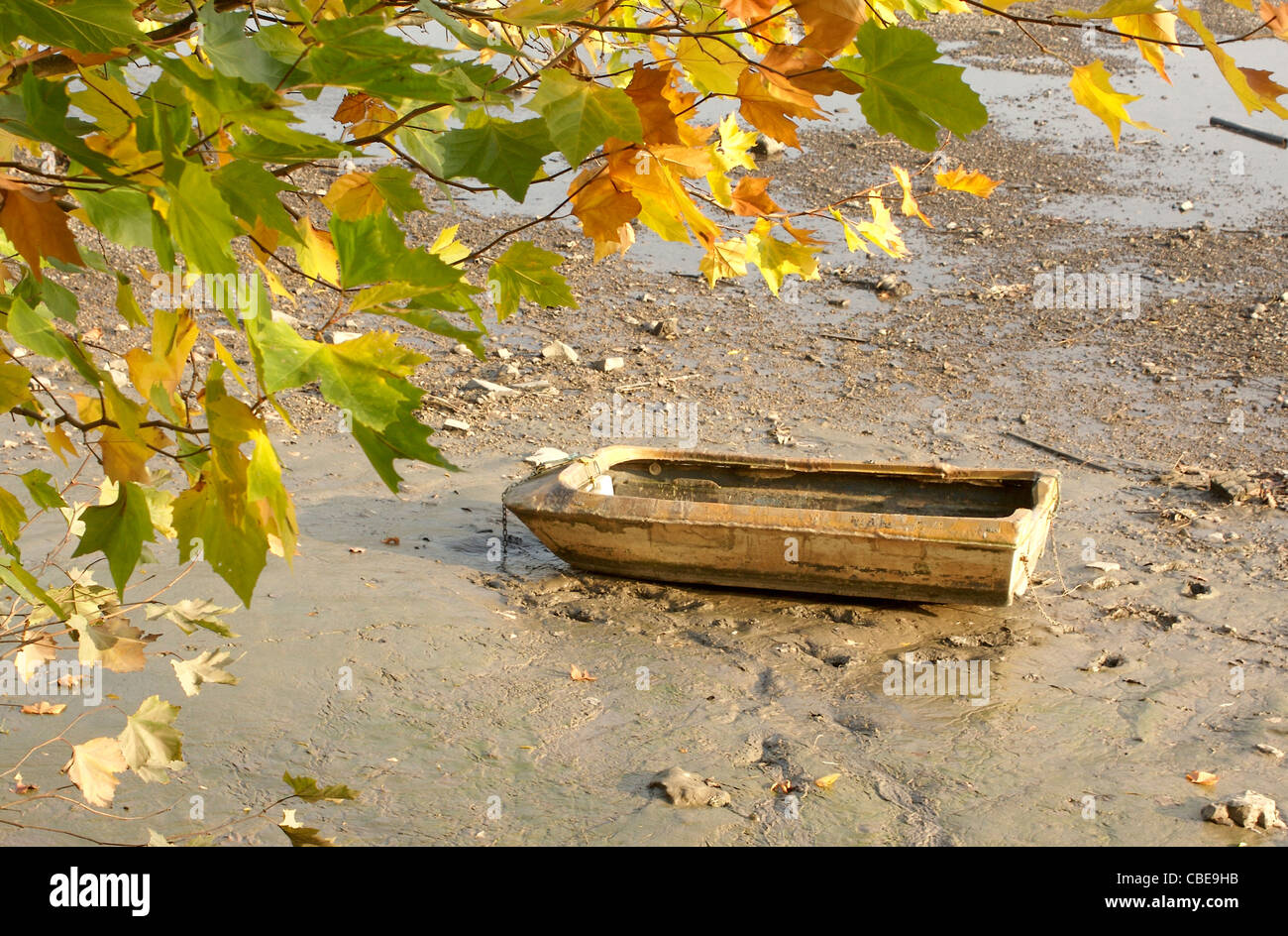 a small row boat sitting on the muddy bottom of the river Thames in ...