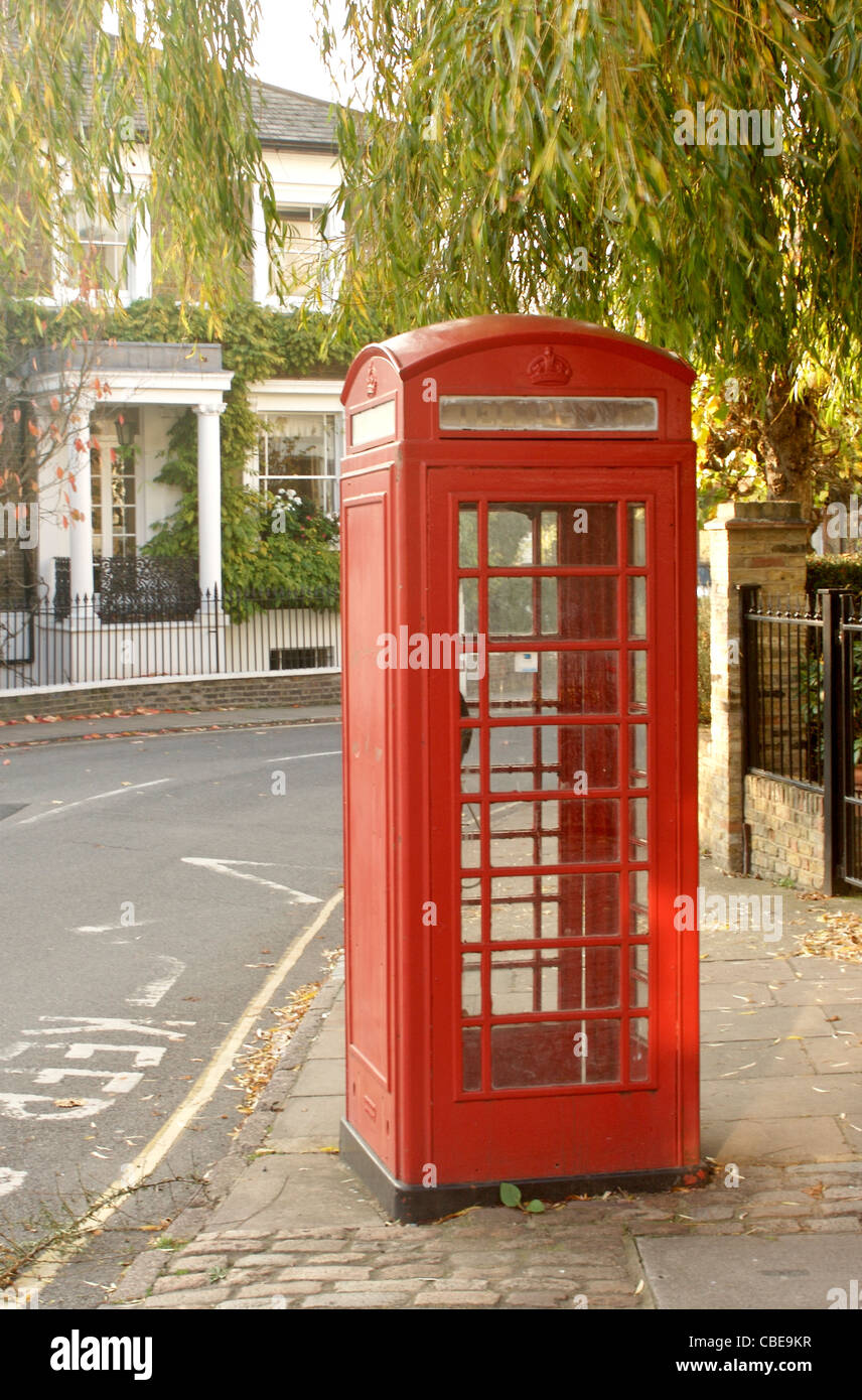 A traditional British red telephone box on a scenic residential street ...