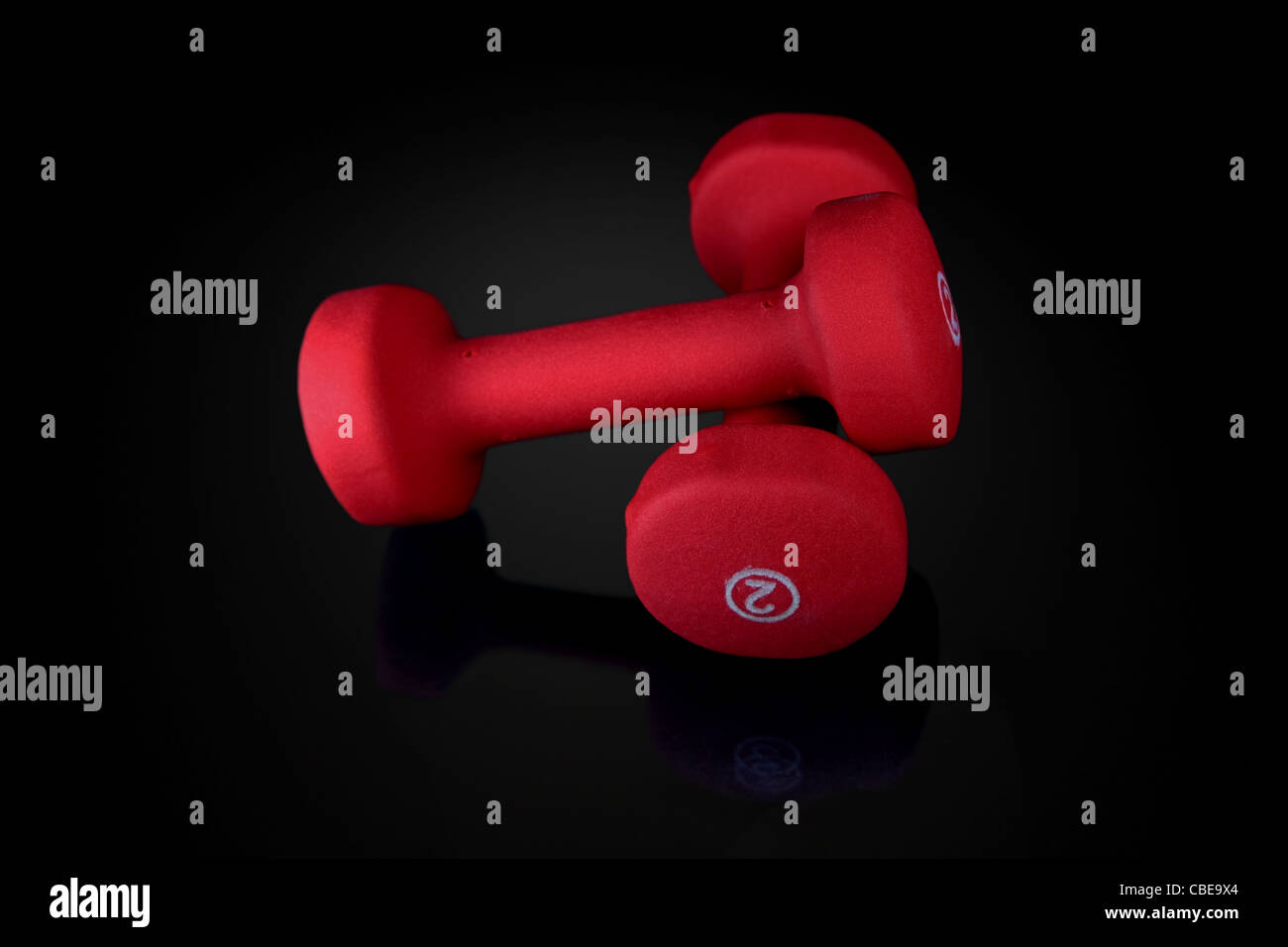 two red hand weights on a dark reflective surface. Low key and copy ...