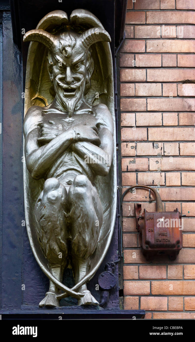Silver-painted crouching figure of a devil with horns and goat's legs ...