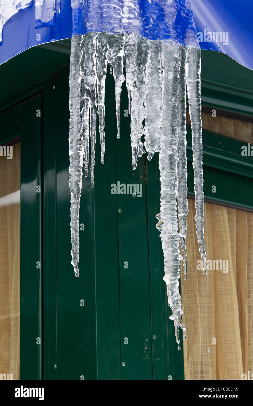 melting icicles and water drops from a metal building with trapulin ...