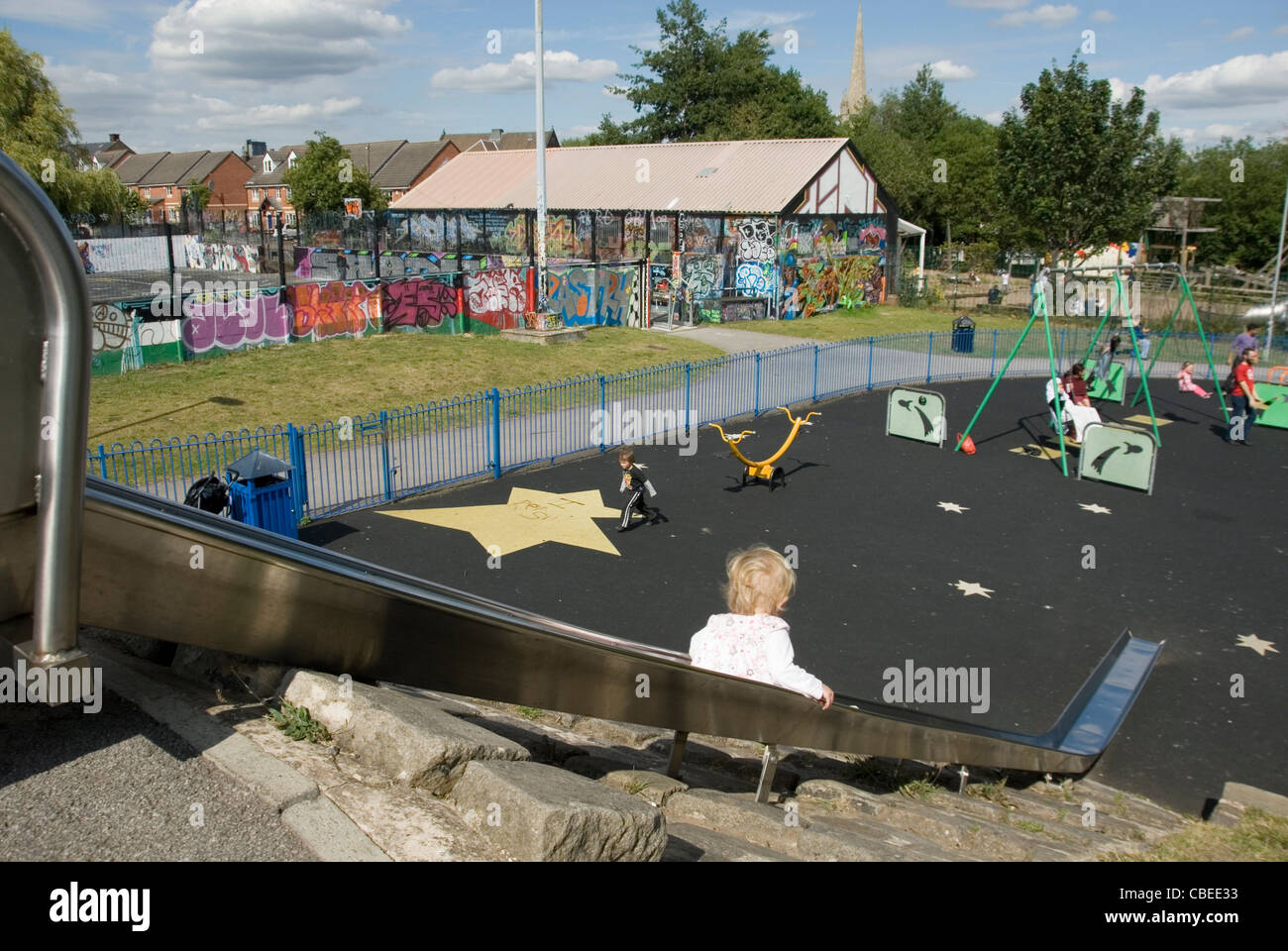 Young Girl Sliding Down Steep Slide Overlooking Children's PLay Park ...