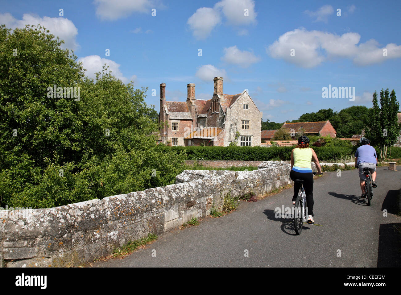 Cyclists crossing the old stone bridge over the River Frome by ...