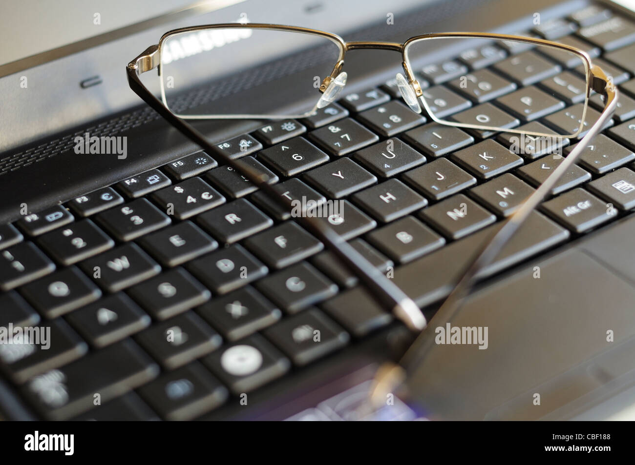 A pair of glasses placed on a black laptop keyboard Stock Photo - Alamy