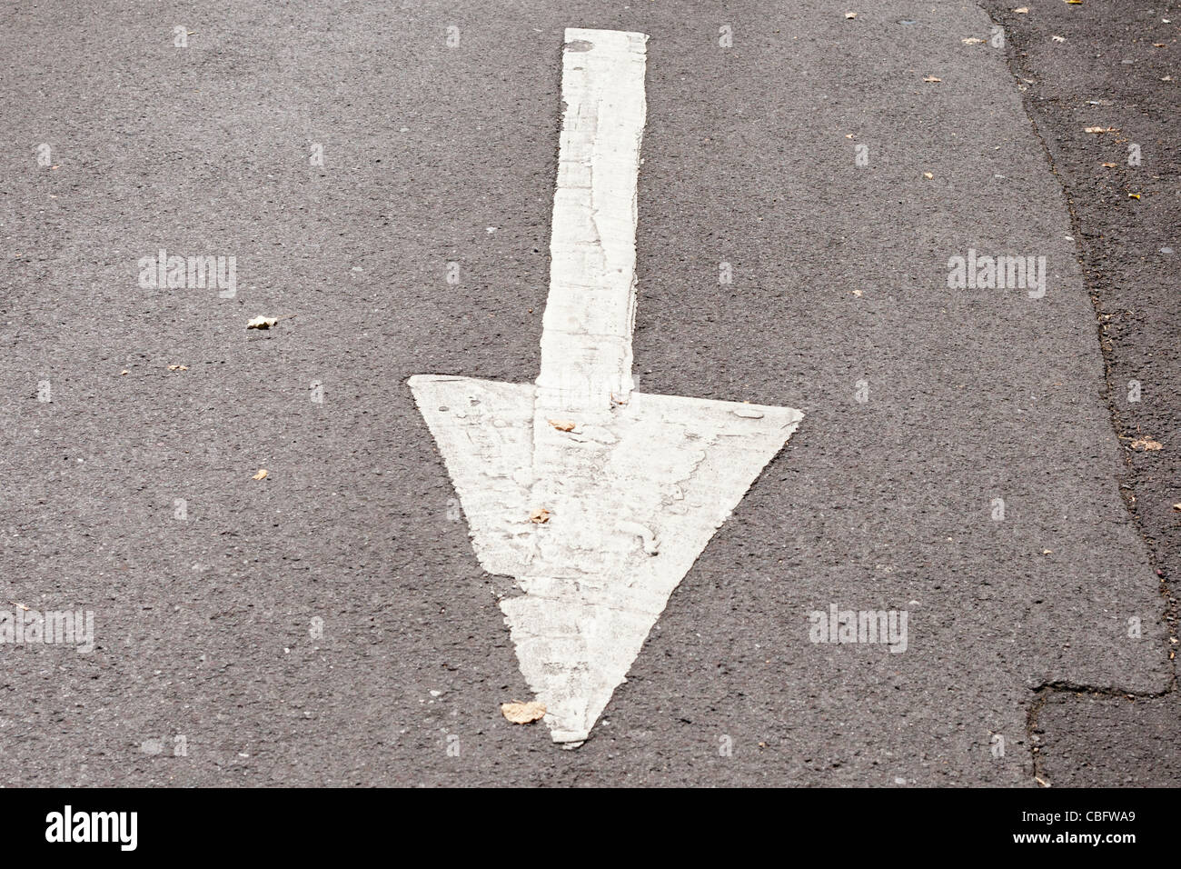 A white directional arrow on grey tarmac Stock Photo - Alamy