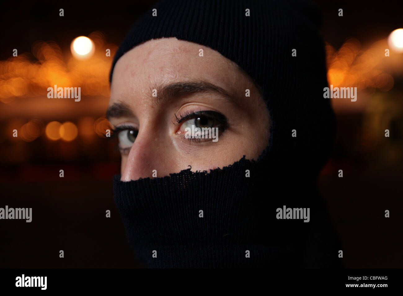 An attractive young woman wearing a black hood mask with some lights in ...
