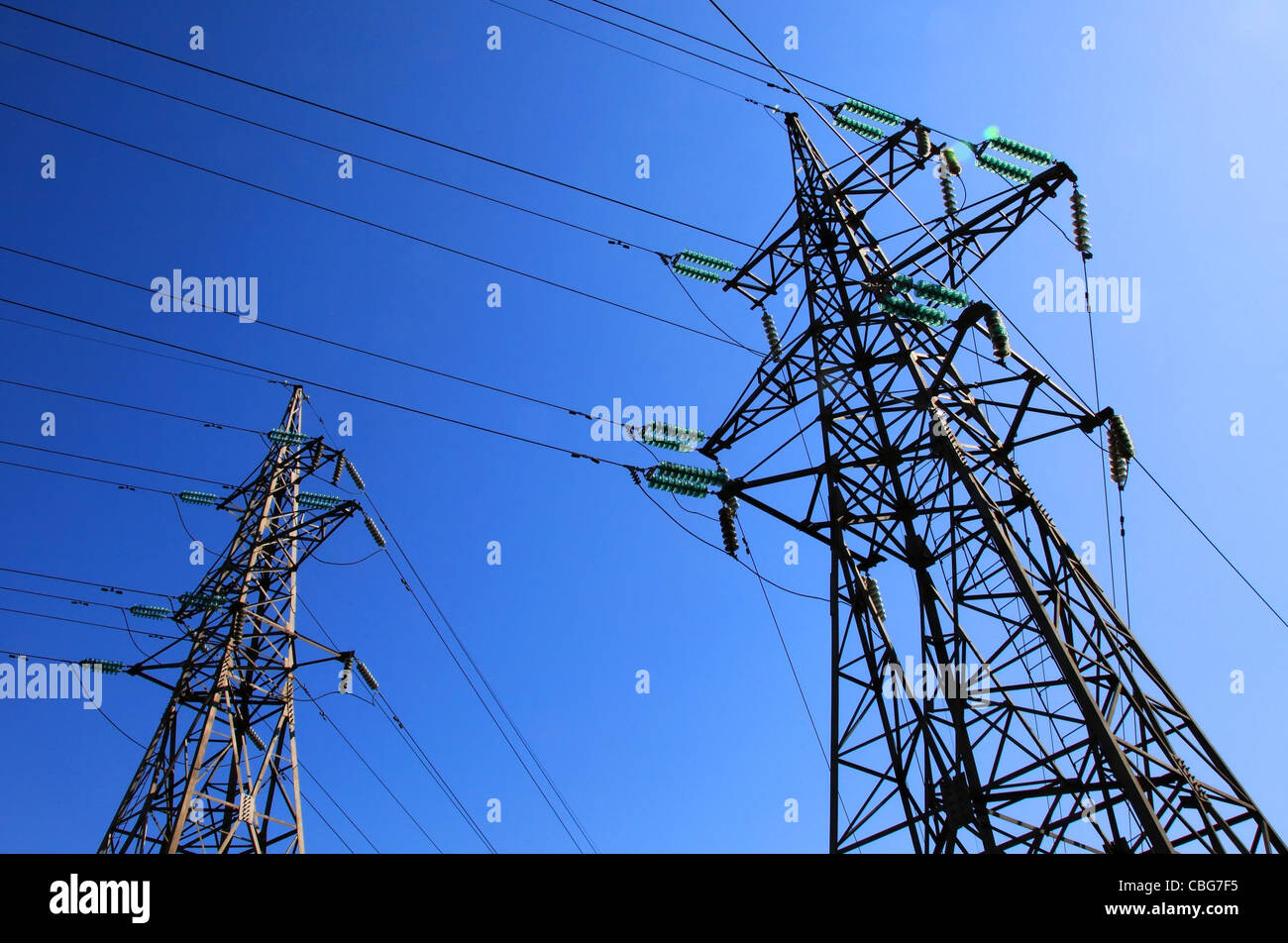 Two electricity pylons against blue sky. Close up Stock Photo - Alamy