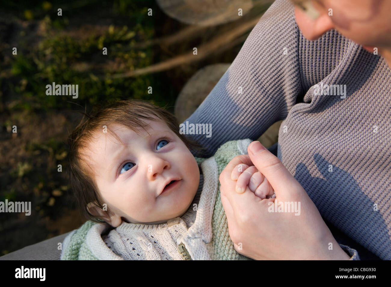 A baby staring up into the face of her mother, focus on baby Stock ...
