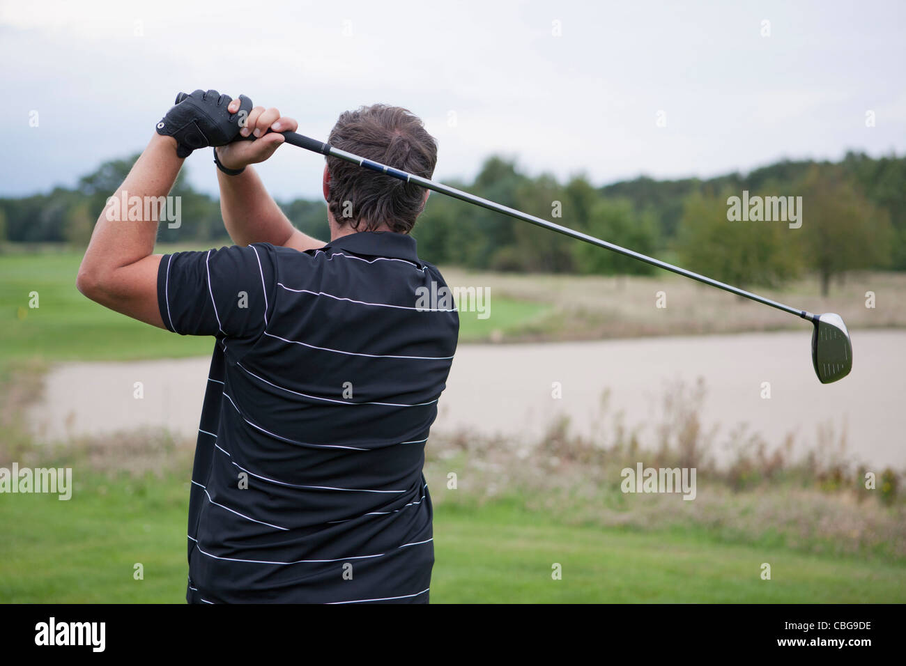 A golfer teeing off, rear view, waist up Stock Photo - Alamy
