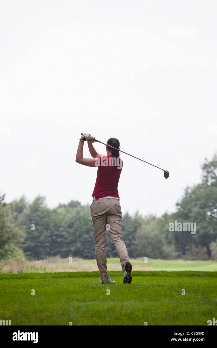 A female golfer teeing off, rear view Stock Photo - Alamy