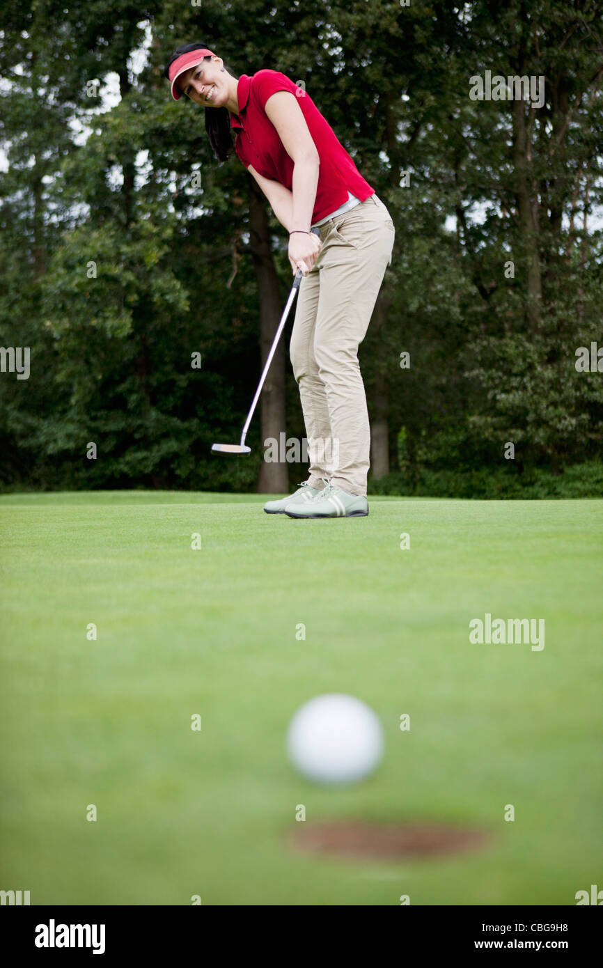 A female golfer putting, golf ball at edge of hole Stock Photo - Alamy