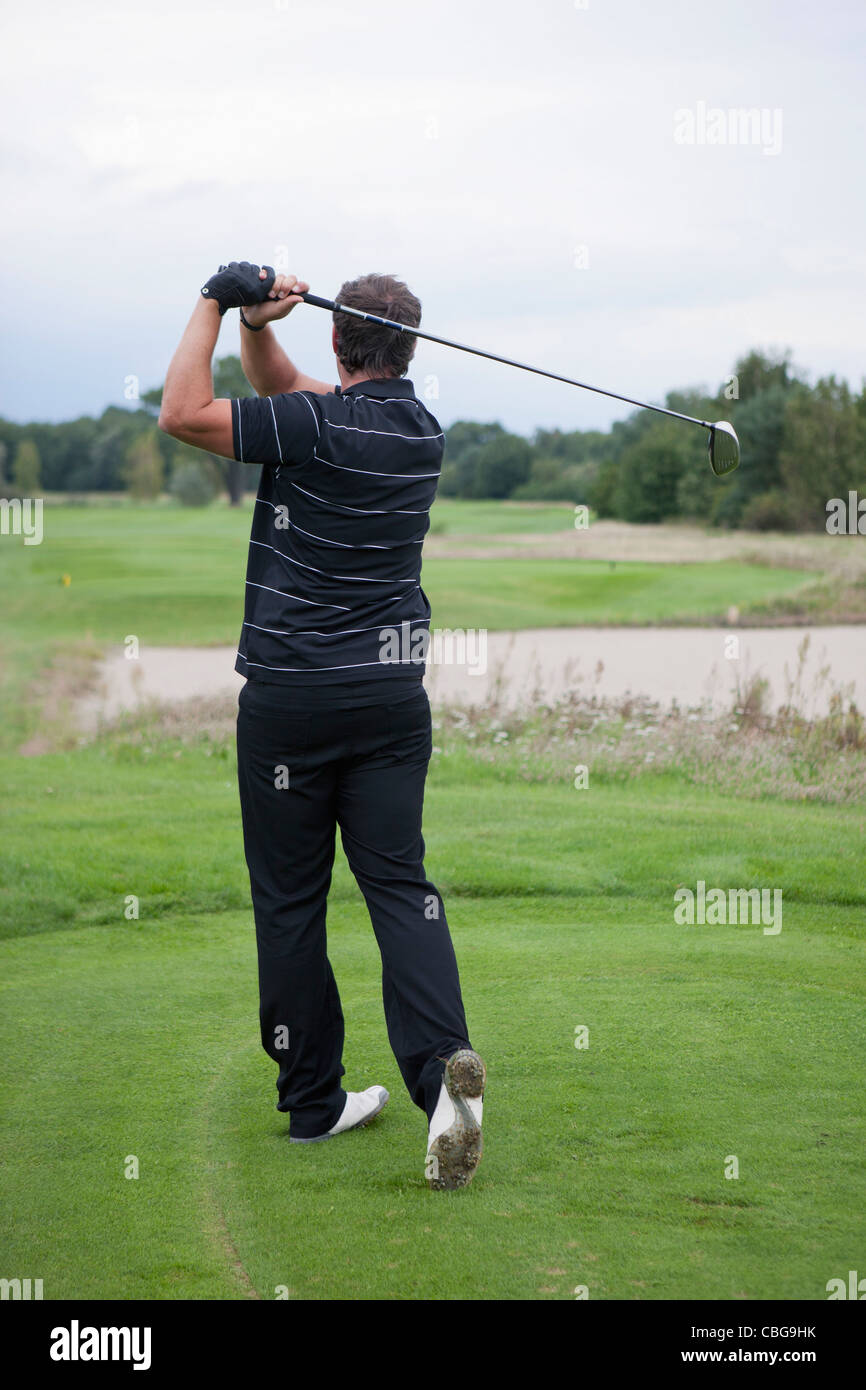 A golfer teeing off, rear view Stock Photo - Alamy