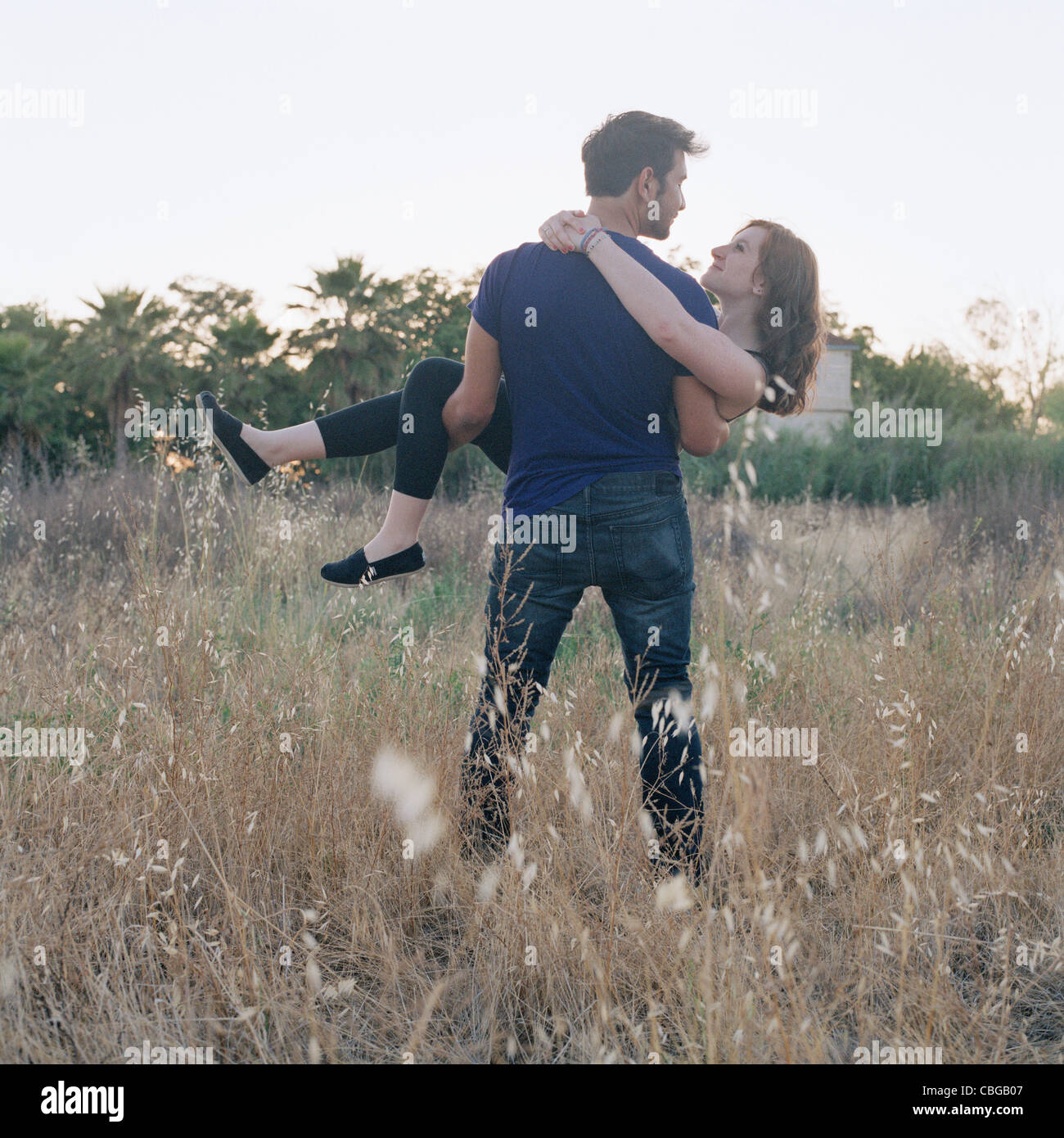 Young man carrying girlfriend through hi-res stock photography and ...