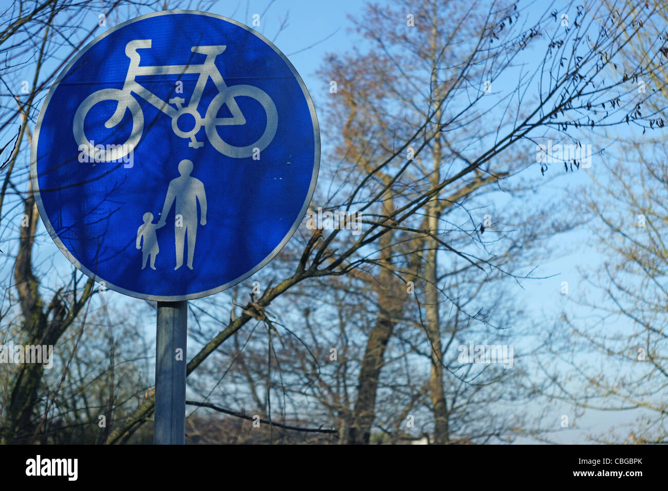 Sign indicating children and bicycles, in dappled sunlight with trees ...