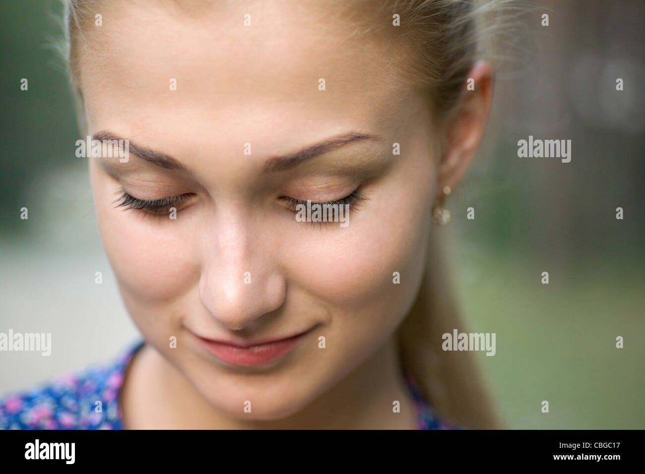 A pretty young woman looking coyly down, close-up Stock Photo - Alamy